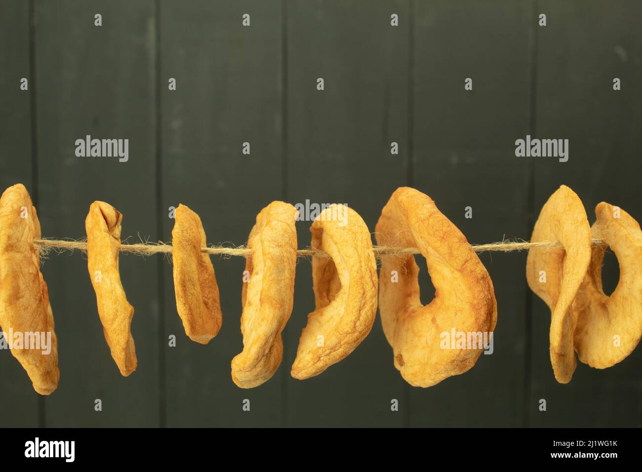 Slices of apples are dried on a rope. Background with copy space ...