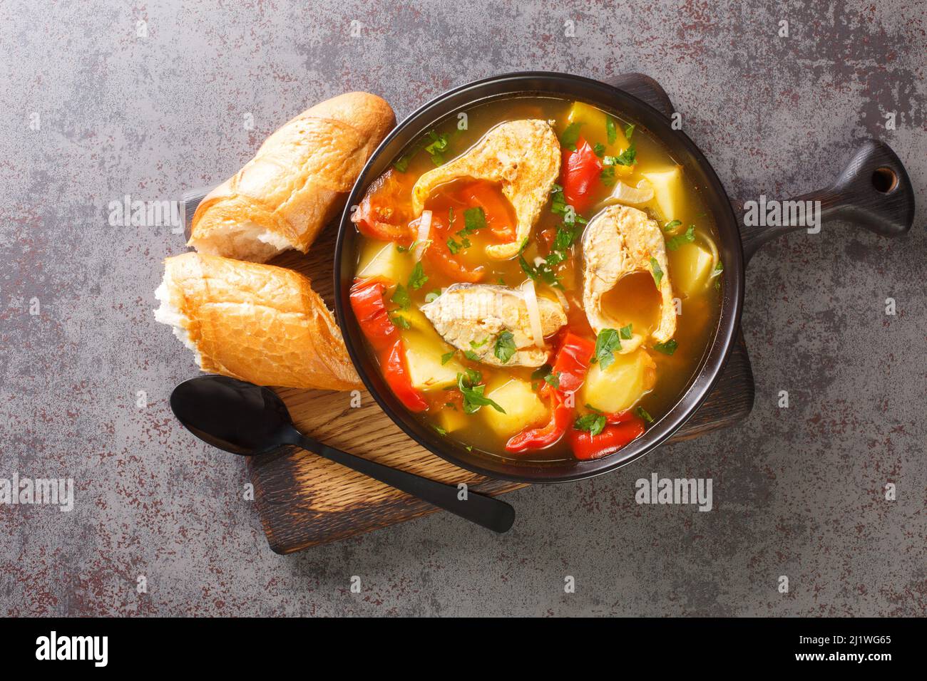 White fish stew with potatoes, peppers, tomatoes and onions close-up in ...