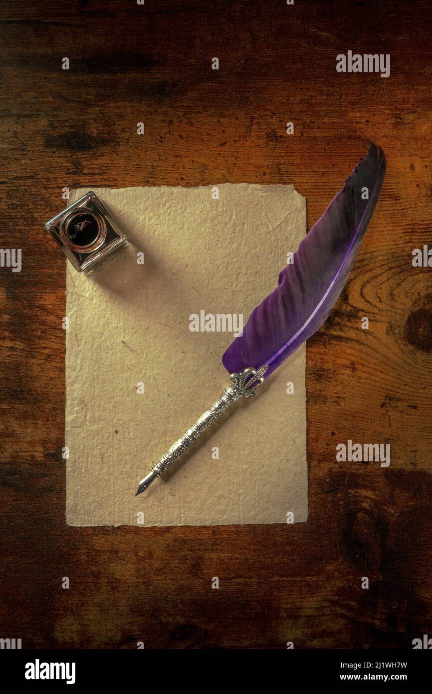 A quill pen with a vintage ink well and a piece of old paper, overhead ...