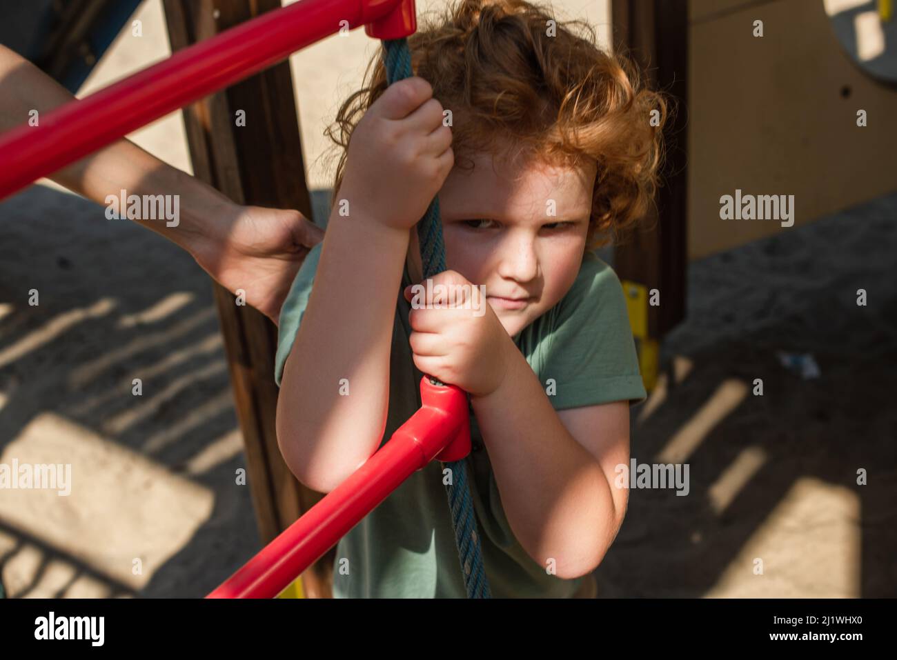 curly boy near rope ladder and mothers hand in amusement park Stock ...