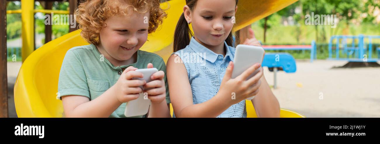 happy kids playing on smartphones on playground, banner Stock Photo - Alamy