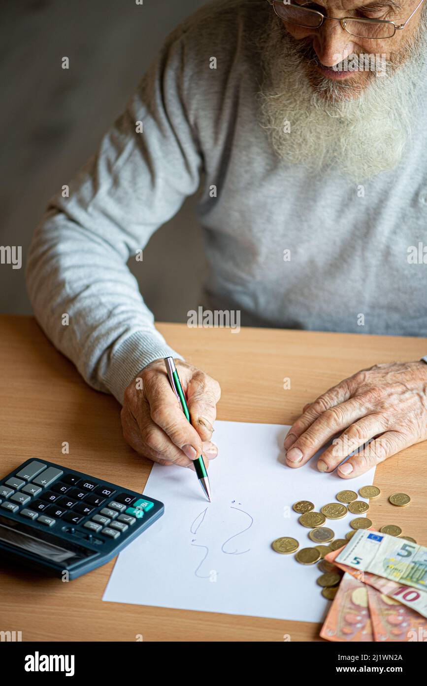 Old bearded senior man with calculator and bills counting euro money ...