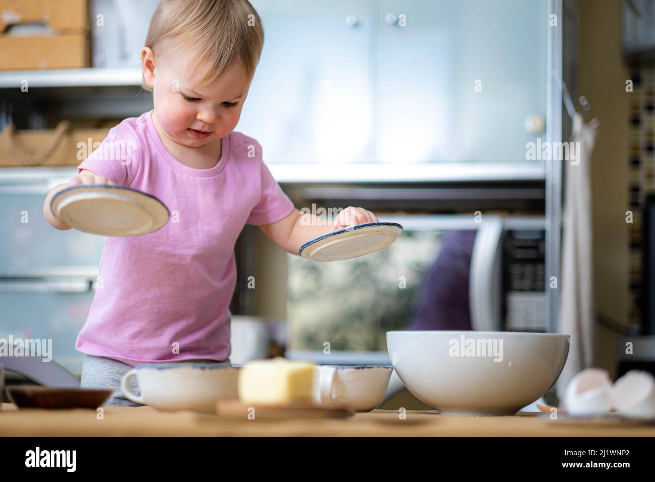 Little cute funny girl helping mother prepare pie cake in kitchen ...