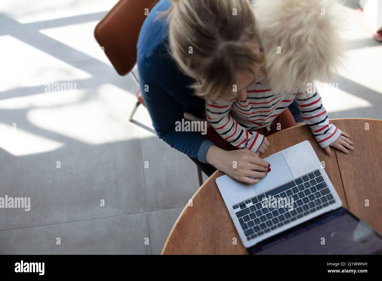 A Mother Working From Home At A Laptop Computer With Her Young Son On