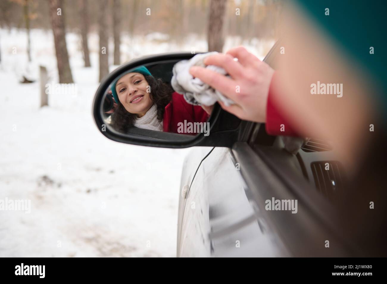 Reflection in the side mirror of beautiful woman in warm winter clothes ...