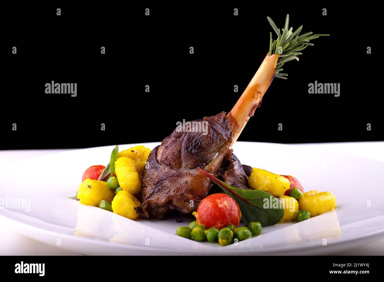 Baked leg of lamb with vegetables, on a white and black background ...