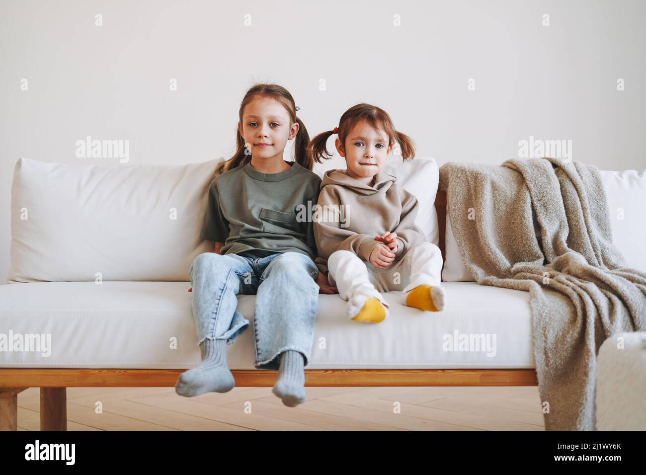 Cure two children girls sisters having fun on couch at the home Stock ...