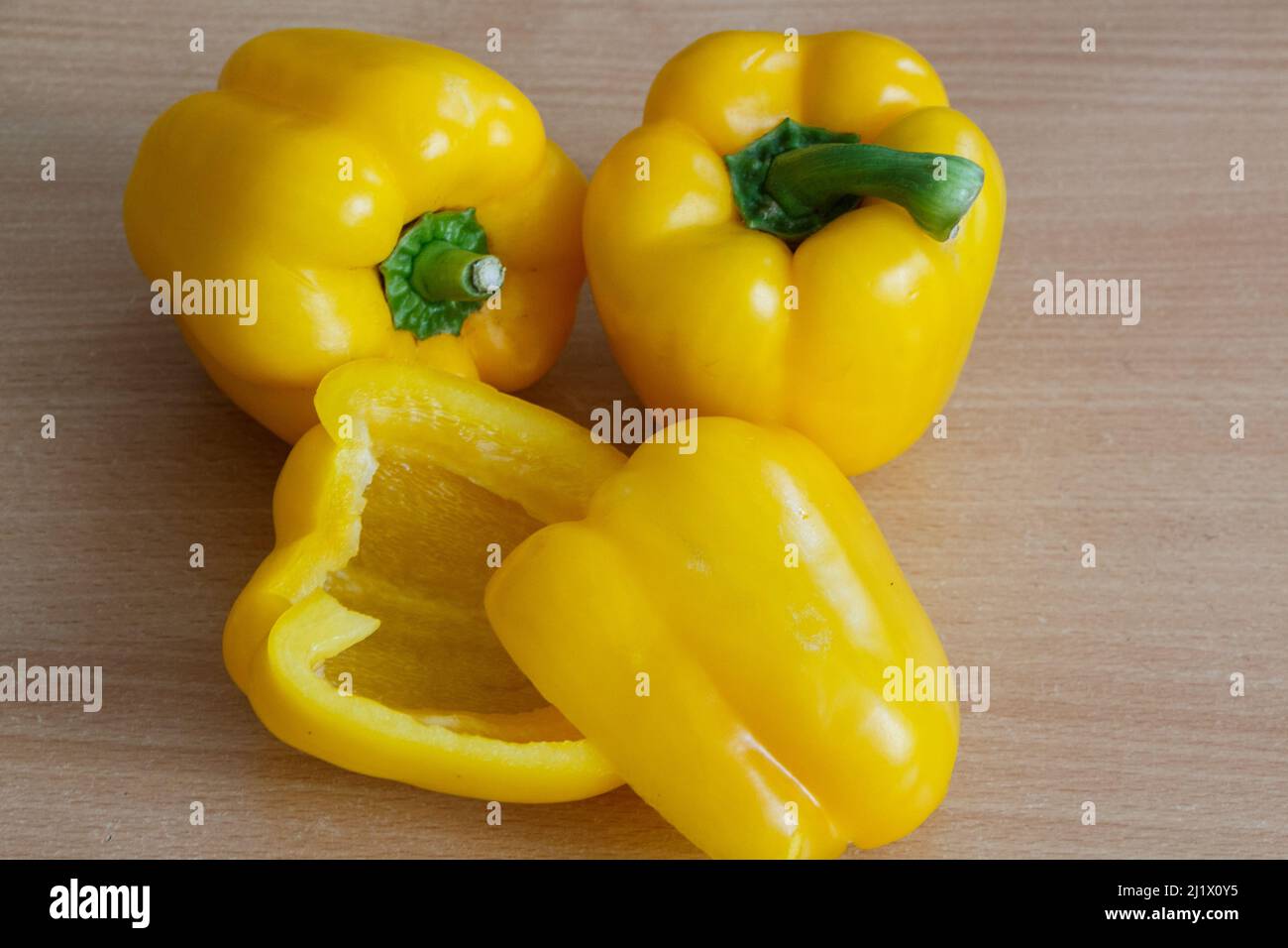 Whole and half yellow peppers on a table Stock Photo - Alamy