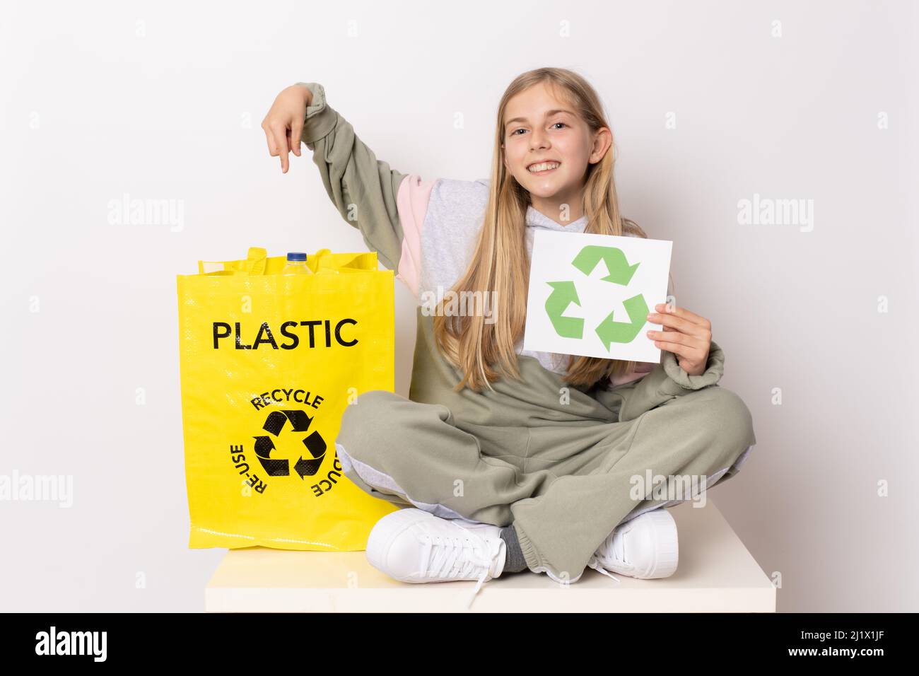Adorable caucasian girl holding recycling sign pointing plastic ...