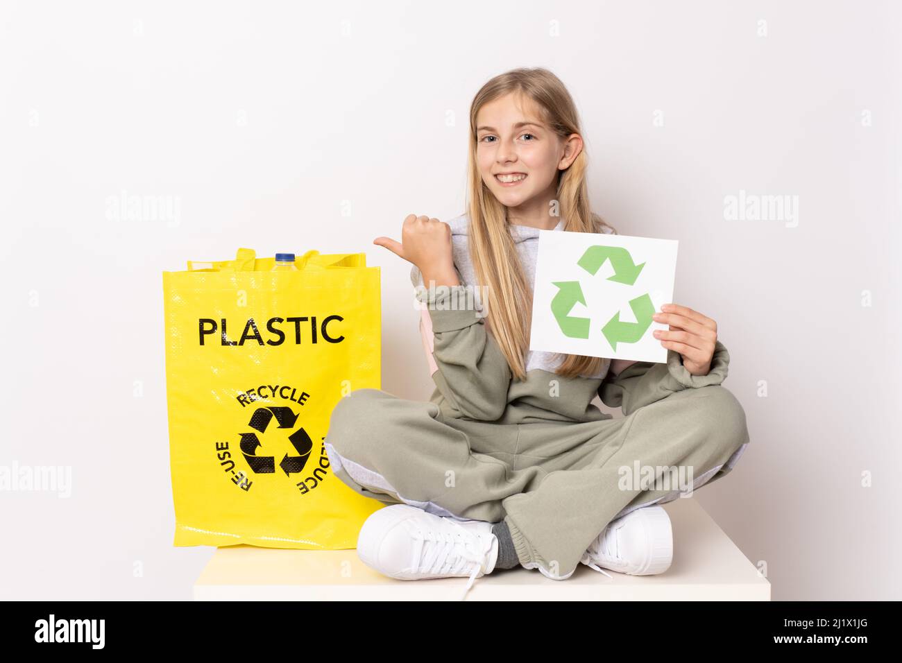 Adorable caucasian girl holding recycling sign pointing plastic ...