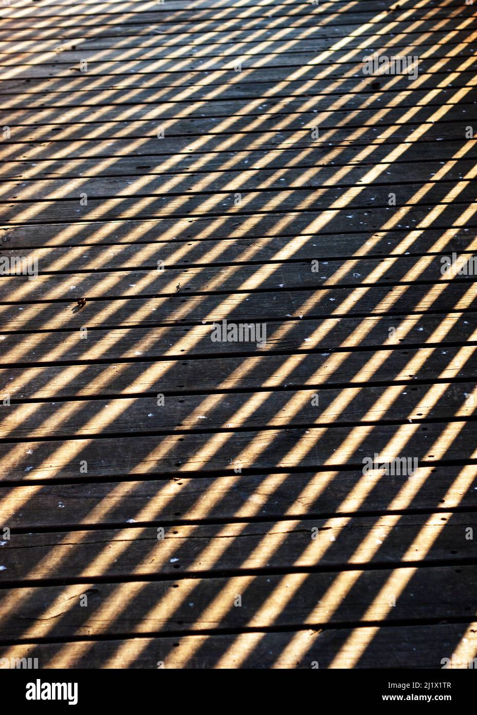 Shadows on wooden walkway with wooden railing forming diagonal boxes ...