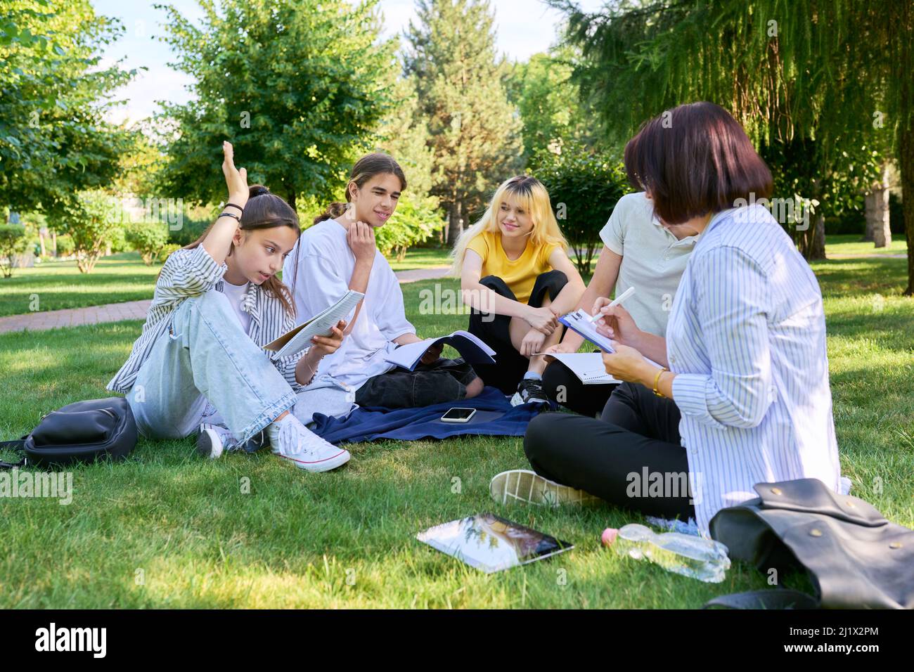 Outdoor, group of students with female teacher sitting on grass Stock ...