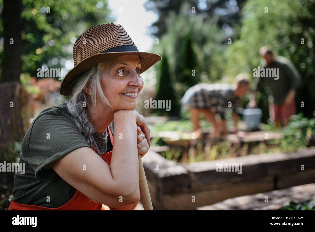Happy young and old farmers working with garden tools outdoors at ...