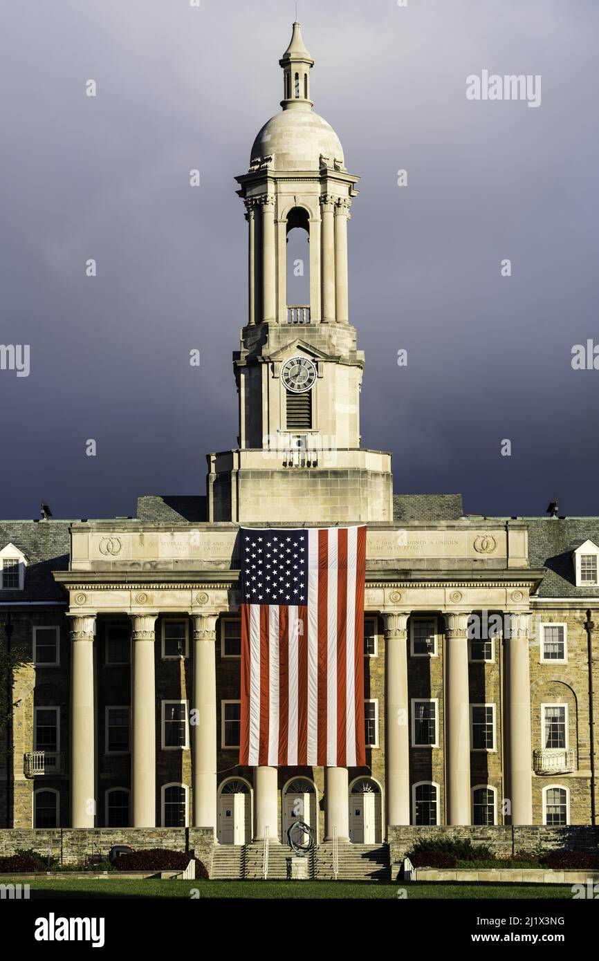 A vertical shot of the Old Main building with the flag of the USA on ...