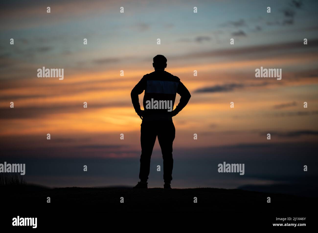 A silhouette of a man standing against the background of sunset Stock ...