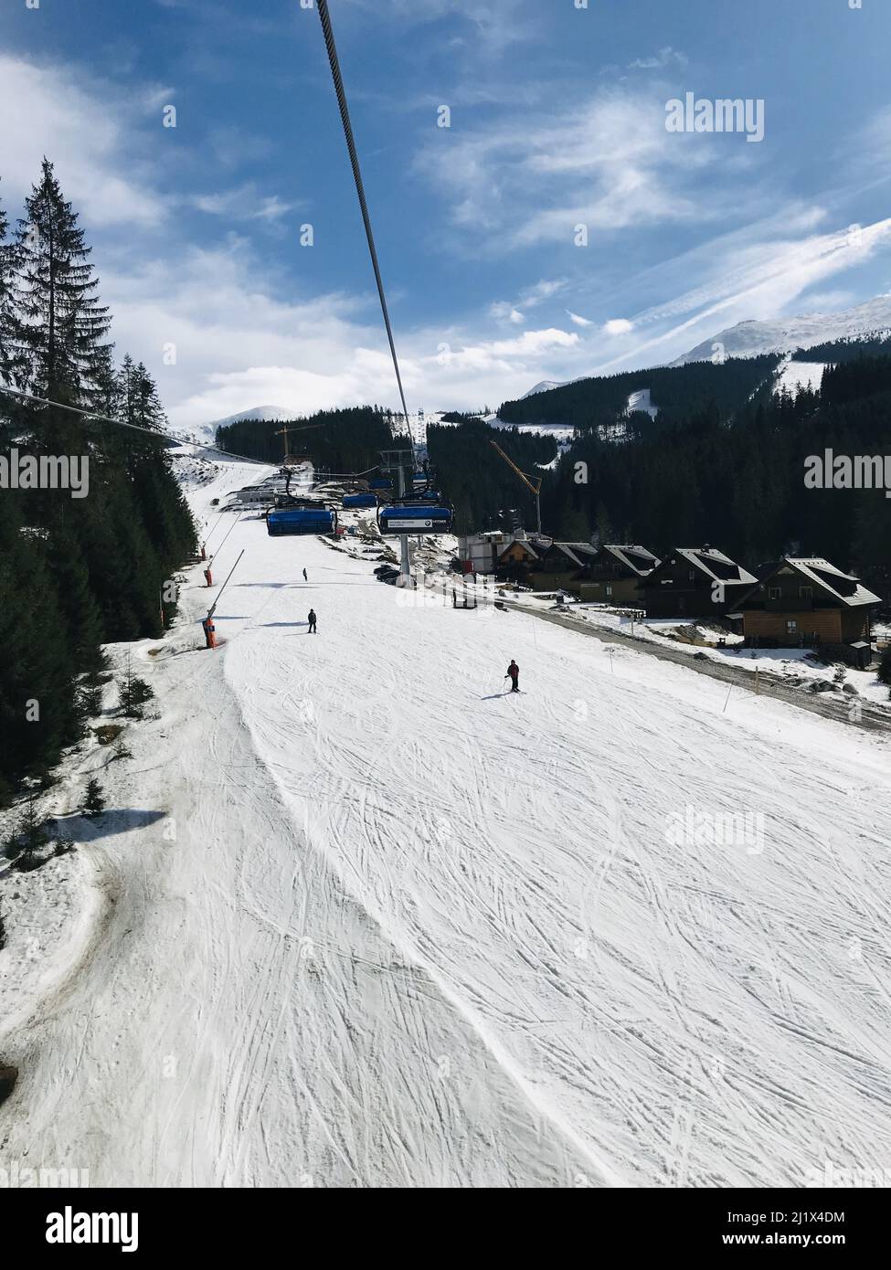 A vertical shot of a winter landscape with a ropeway on cloudy sky ...