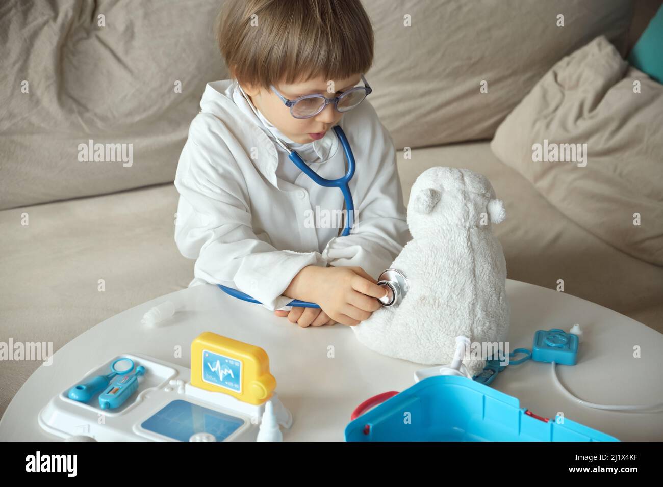 Little doctor in medical coat with stethoscope play an examination of ...