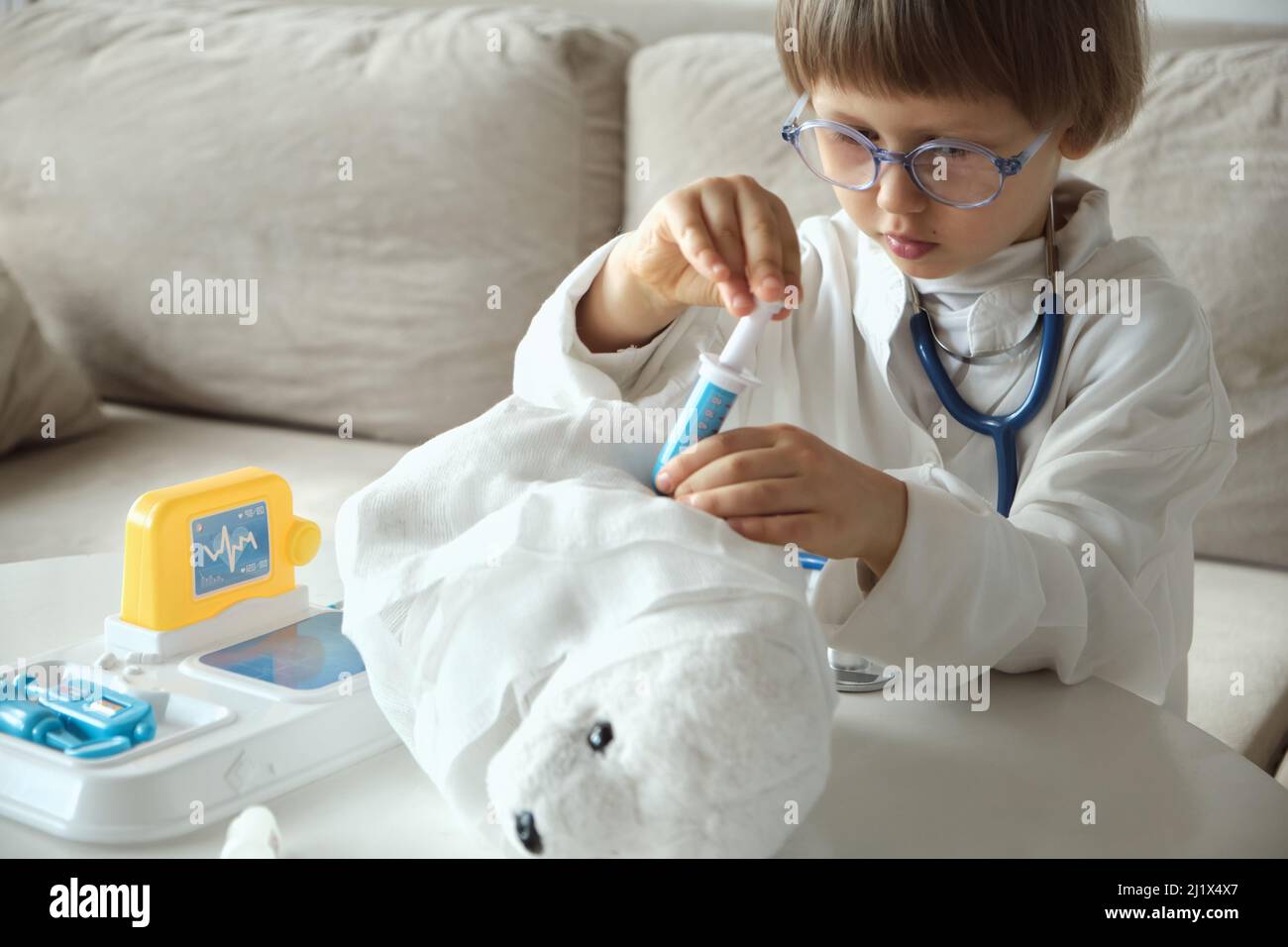 Little doctor in medical coat with stethoscope play an injection to ...