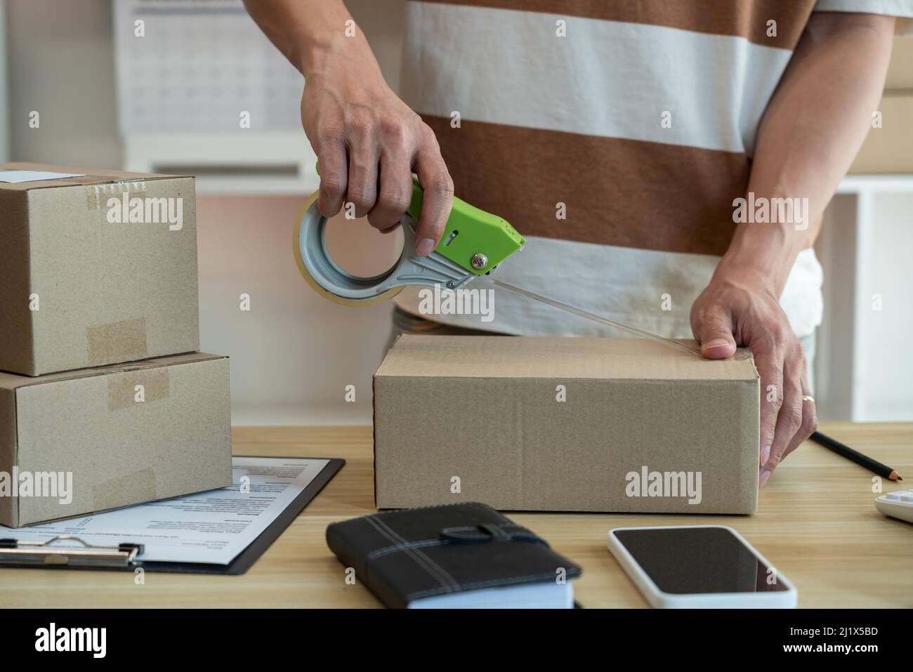 Online shopping concept the shop seller sealing the parcel of his goods ...