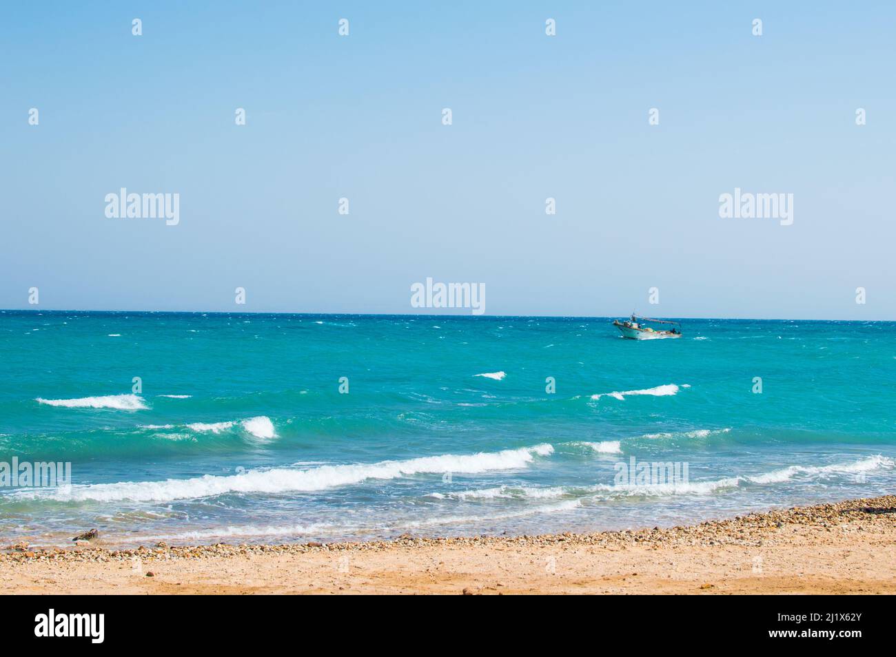 The calm blue sea with a single ship near an empty, sandy shore Stock ...