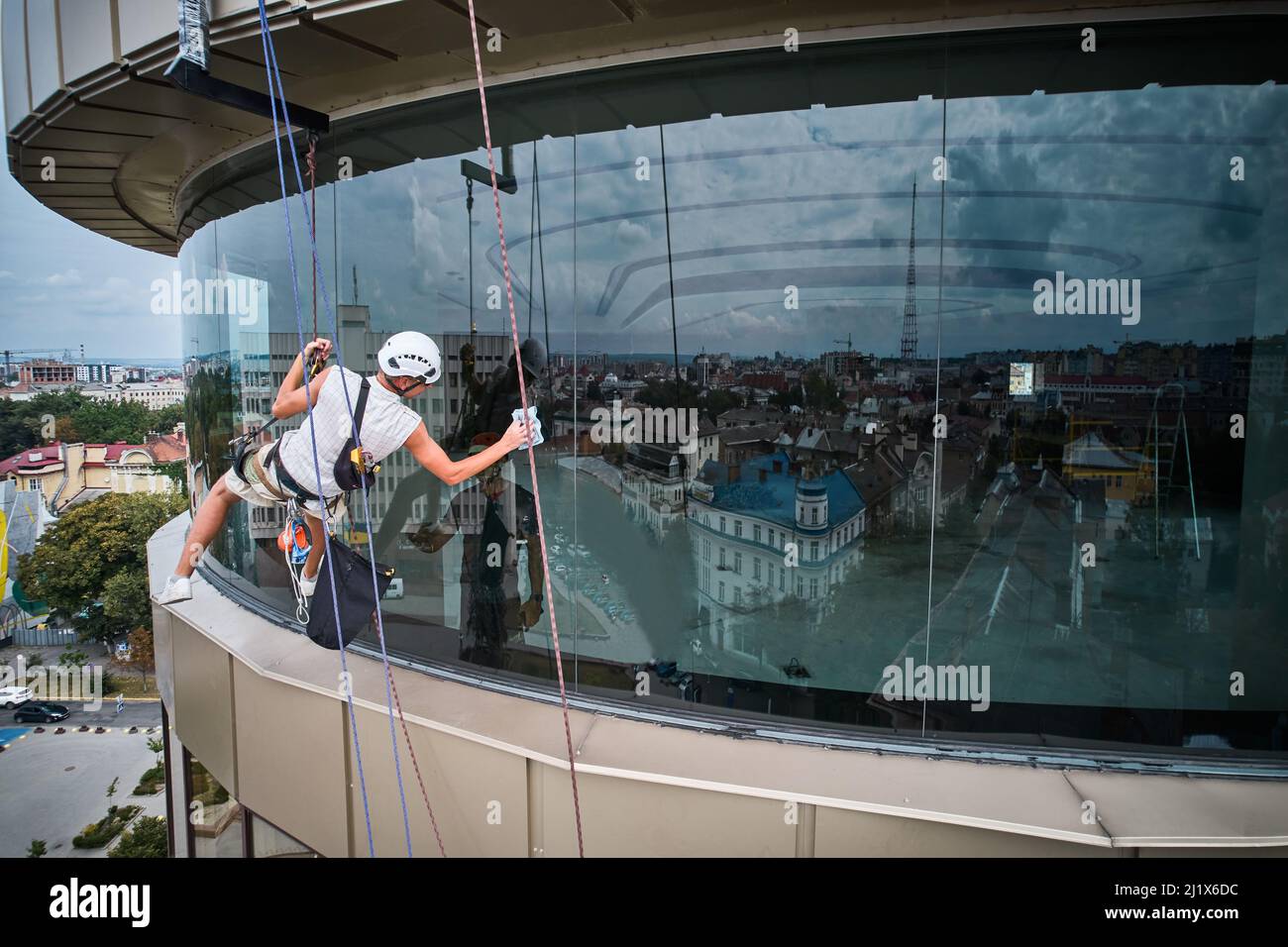 Industrial mountaineering worker cleaning window of high-rise building ...