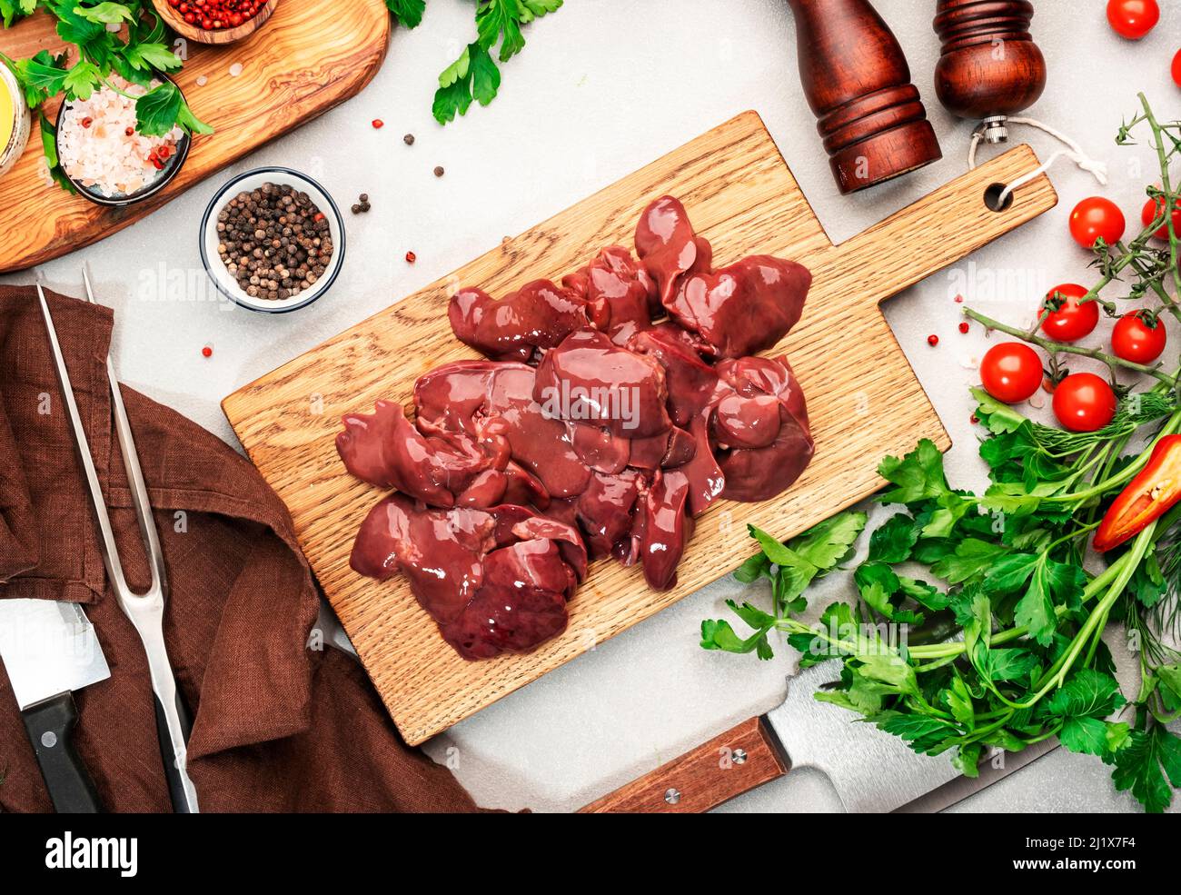 Fresh raw chicken liver on cutting board and ingredients for cooking on ...