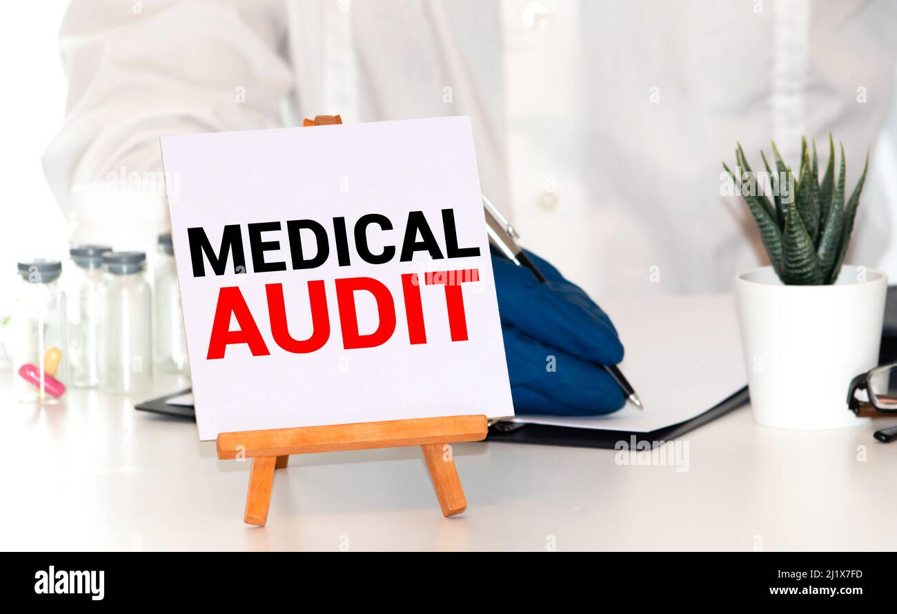 Doctor holding a business card with capital lettering MEDICAL AUDIT in ...