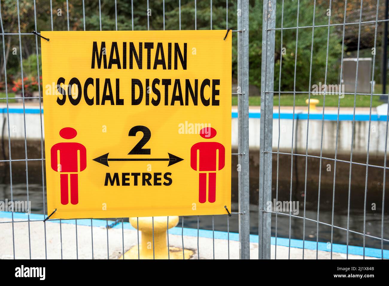 Close up of a social distance warning sign fixed to a metal fence in a ...