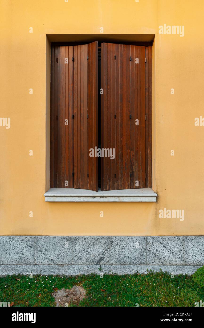 A vertical shot of a brown wooden window cover on a yellow wall Stock ...
