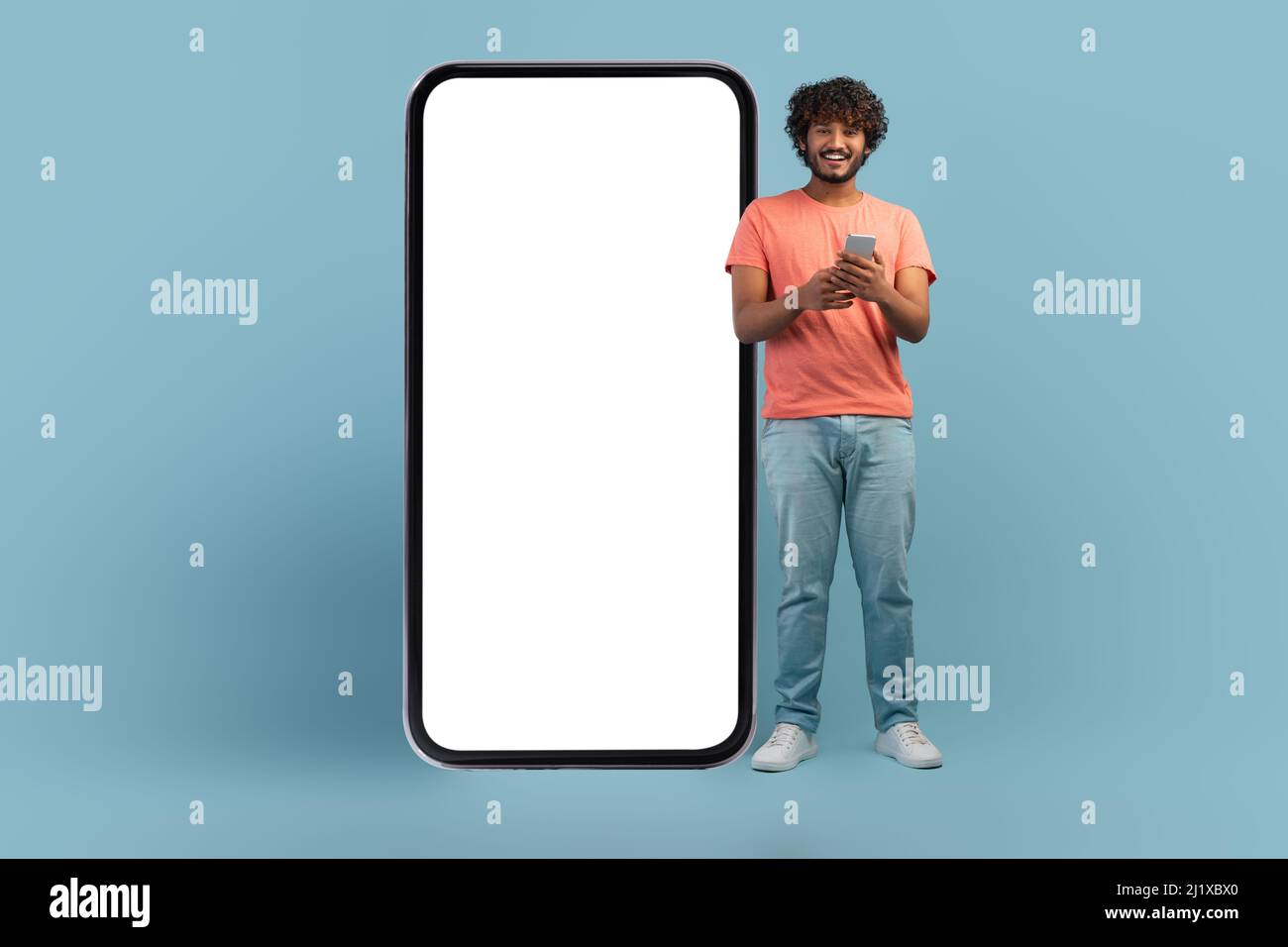 Happy young indian man using cell phone on blue Stock Photo - Alamy