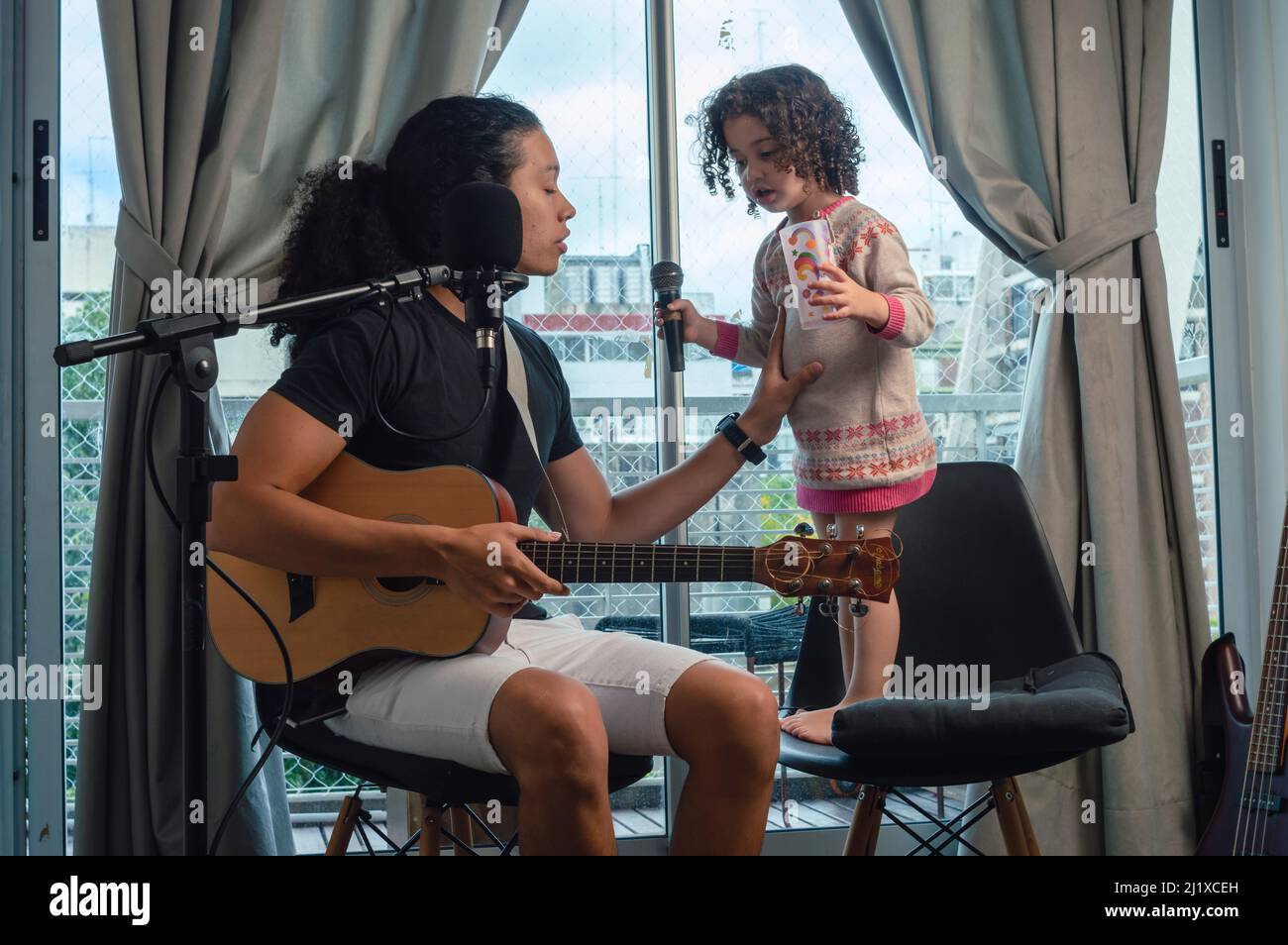 young caucasian singer man sitting with his guitar teaches his daughter ...