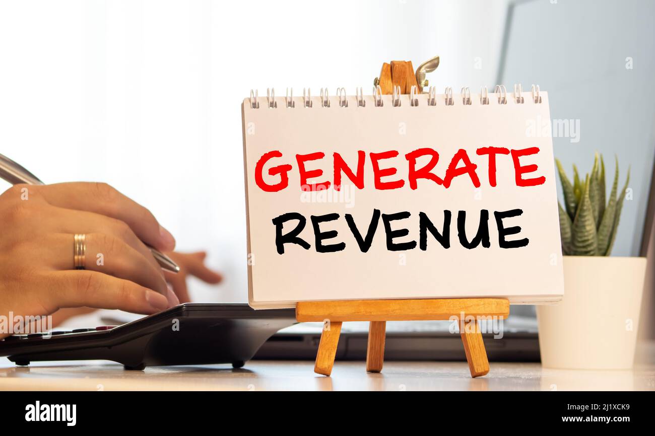 Red pen and notepad with text GENERATE REVENUE in the white background ...