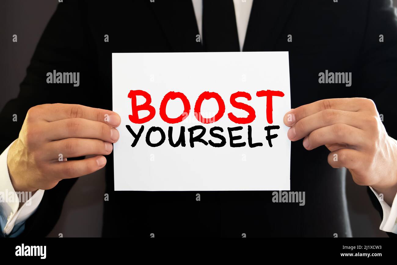 BOOST YOURSELF, message on the card shown by a man Stock Photo - Alamy