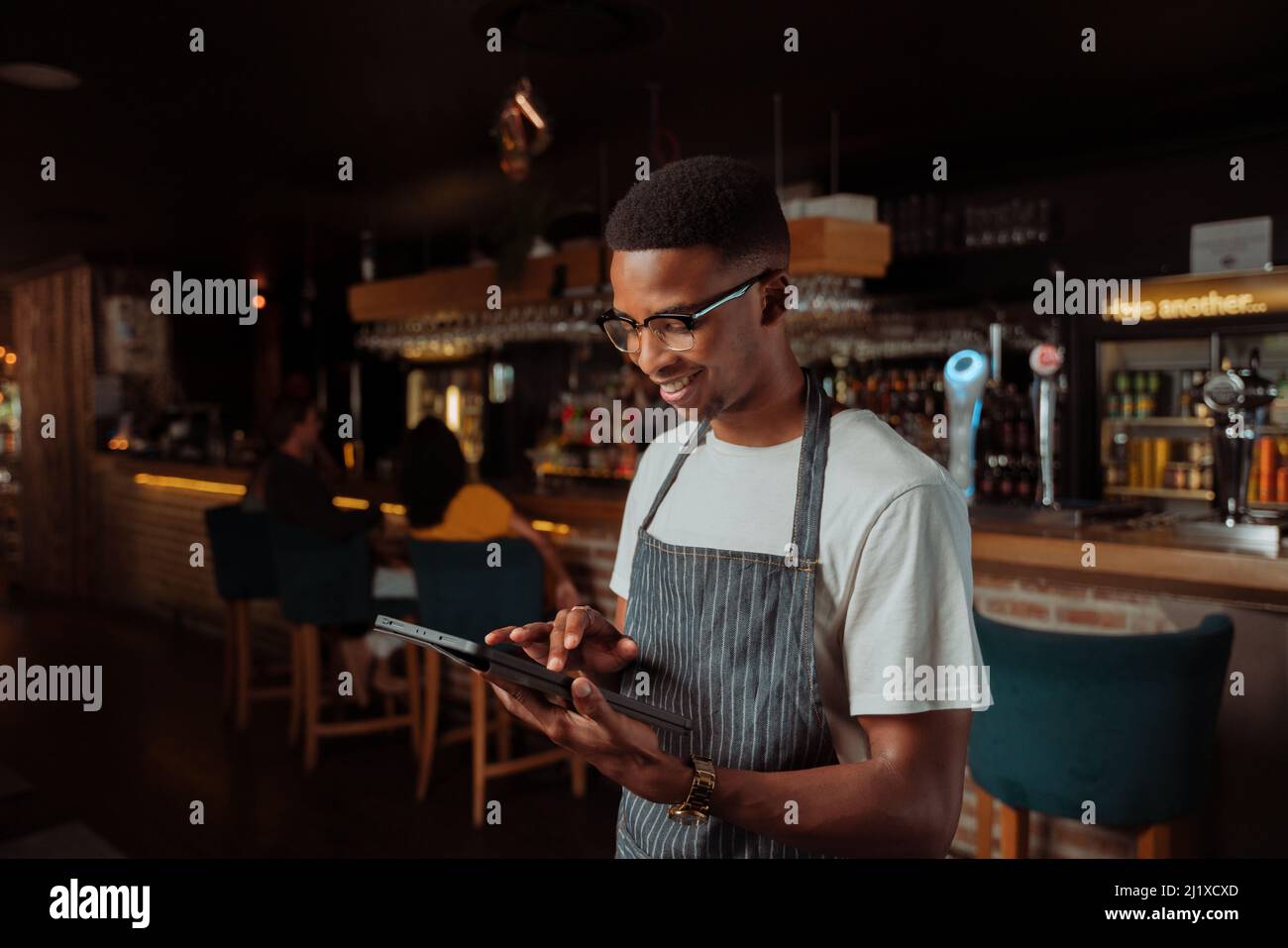 African American waiter working in restaurant holding digital tablet ...