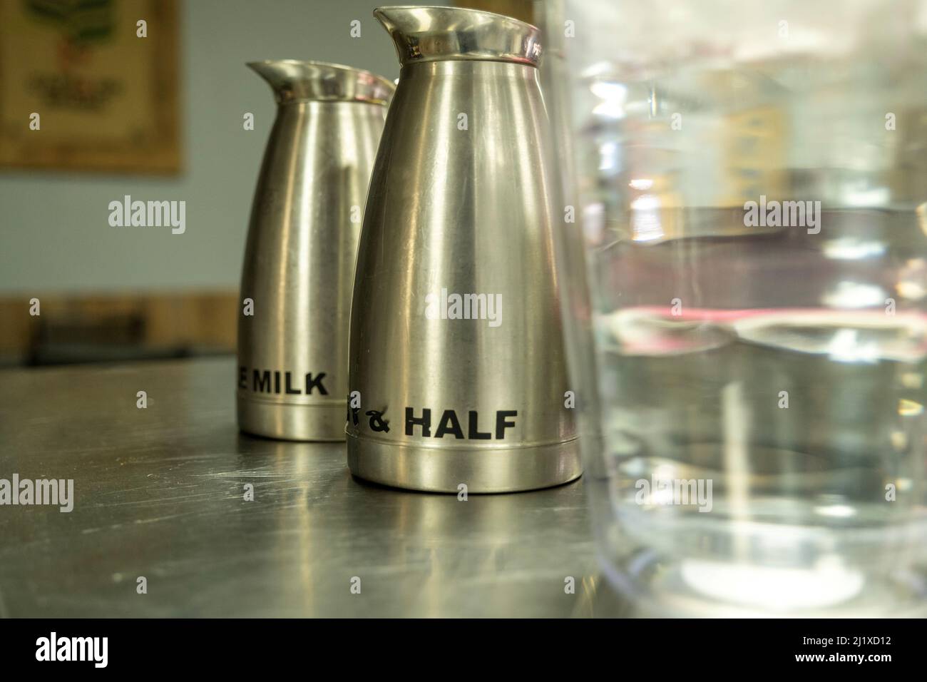 Milk and Half and Half pitchers next to an out of focus water container ...
