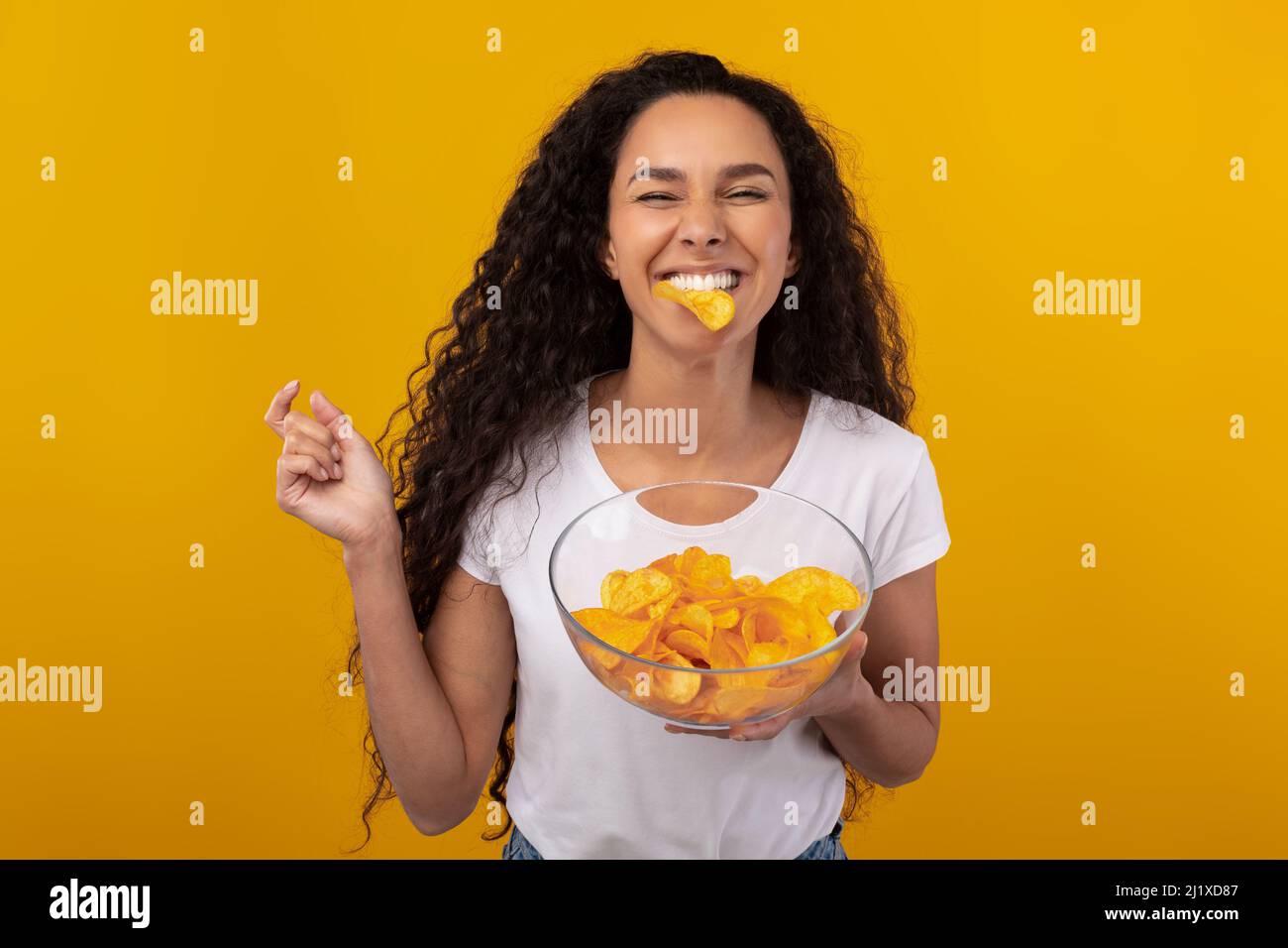 Excited Latin Lady Eating Delicious Potato Crisps Stock Photo - Alamy