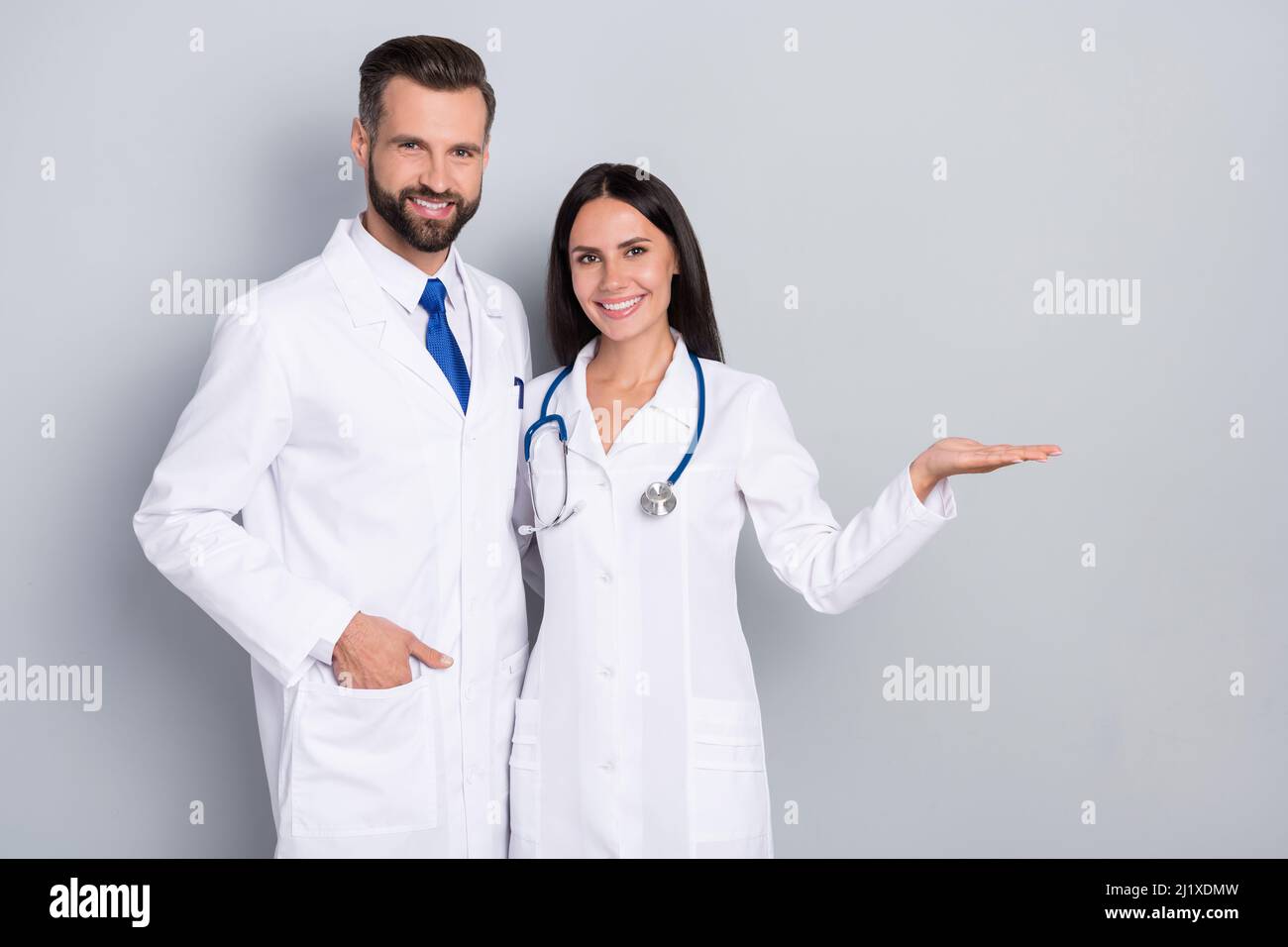 Portrait of two attractive cheerful doctors hugging holding on palm copy space cure isolated ...