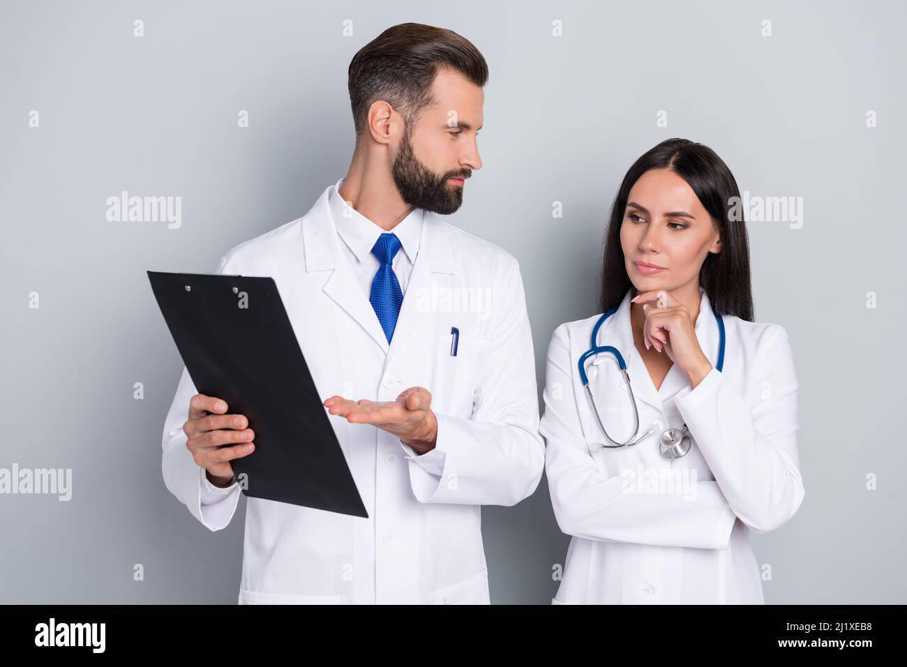 Portrait of two attractive skilled smart doctors reading analyzing ...