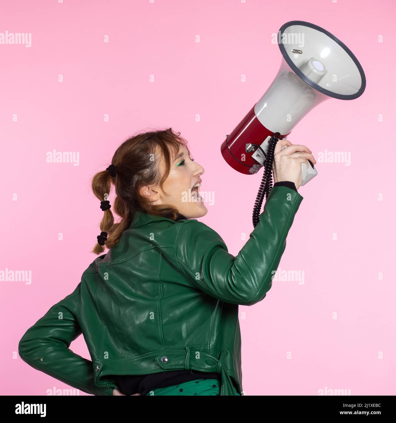 Funny young female shouting through megaphone. Young woman using ...