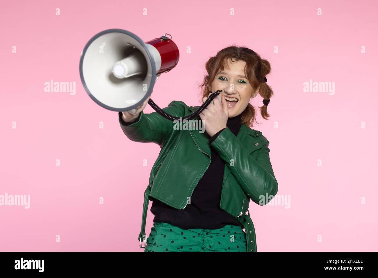 Funny young female shouting through megaphone. Young woman using ...