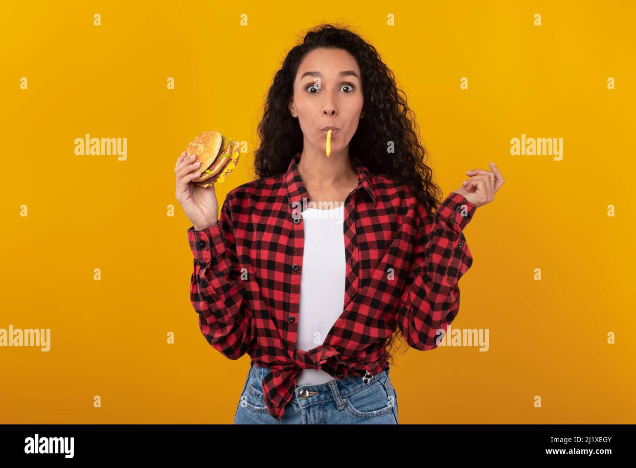 Excited Lady Eating Delicious French Fries And Burger Stock Photo - Alamy