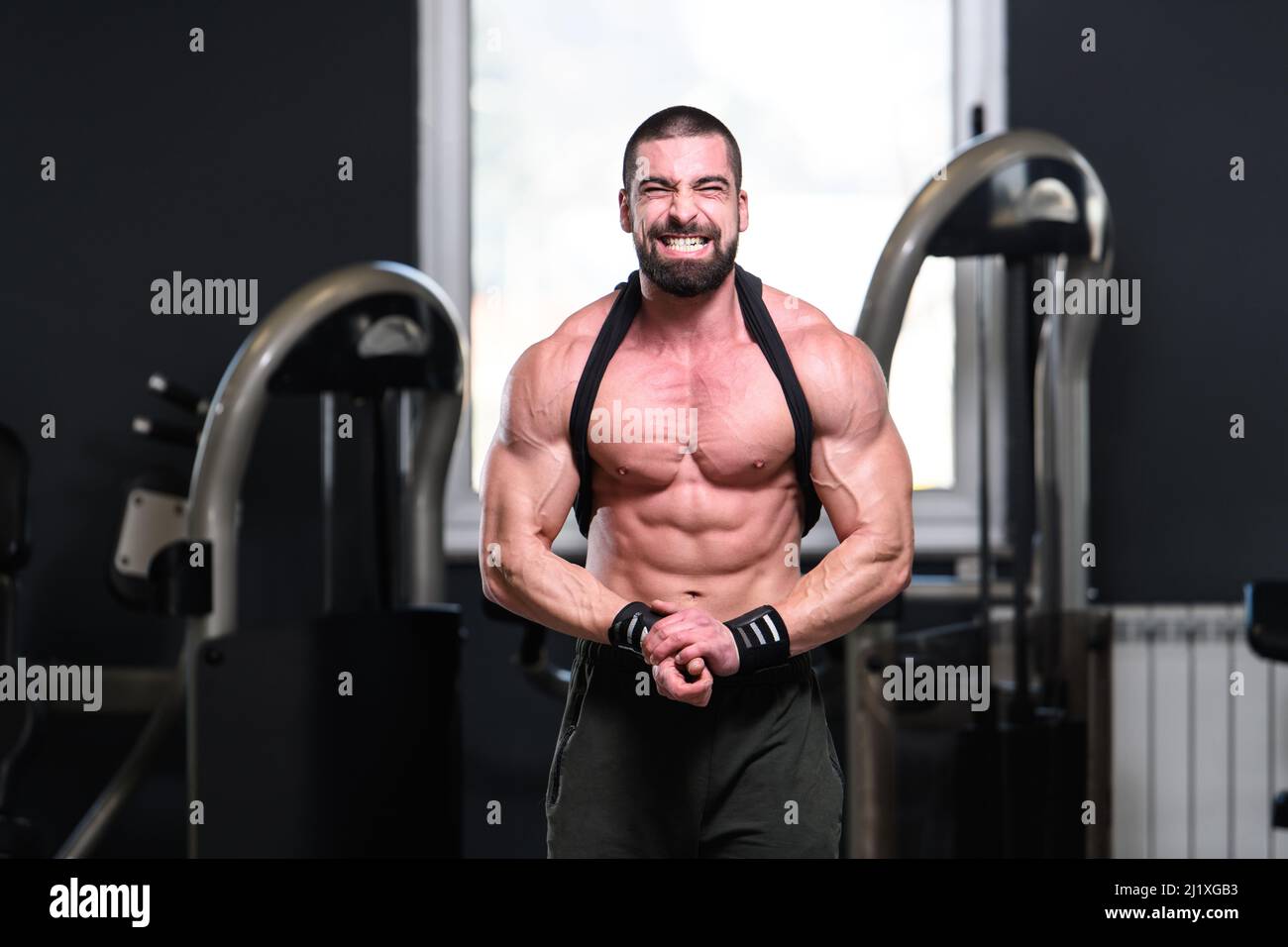 Handsome Young Man Standing Strong In The Gym And Flexing Muscles ...