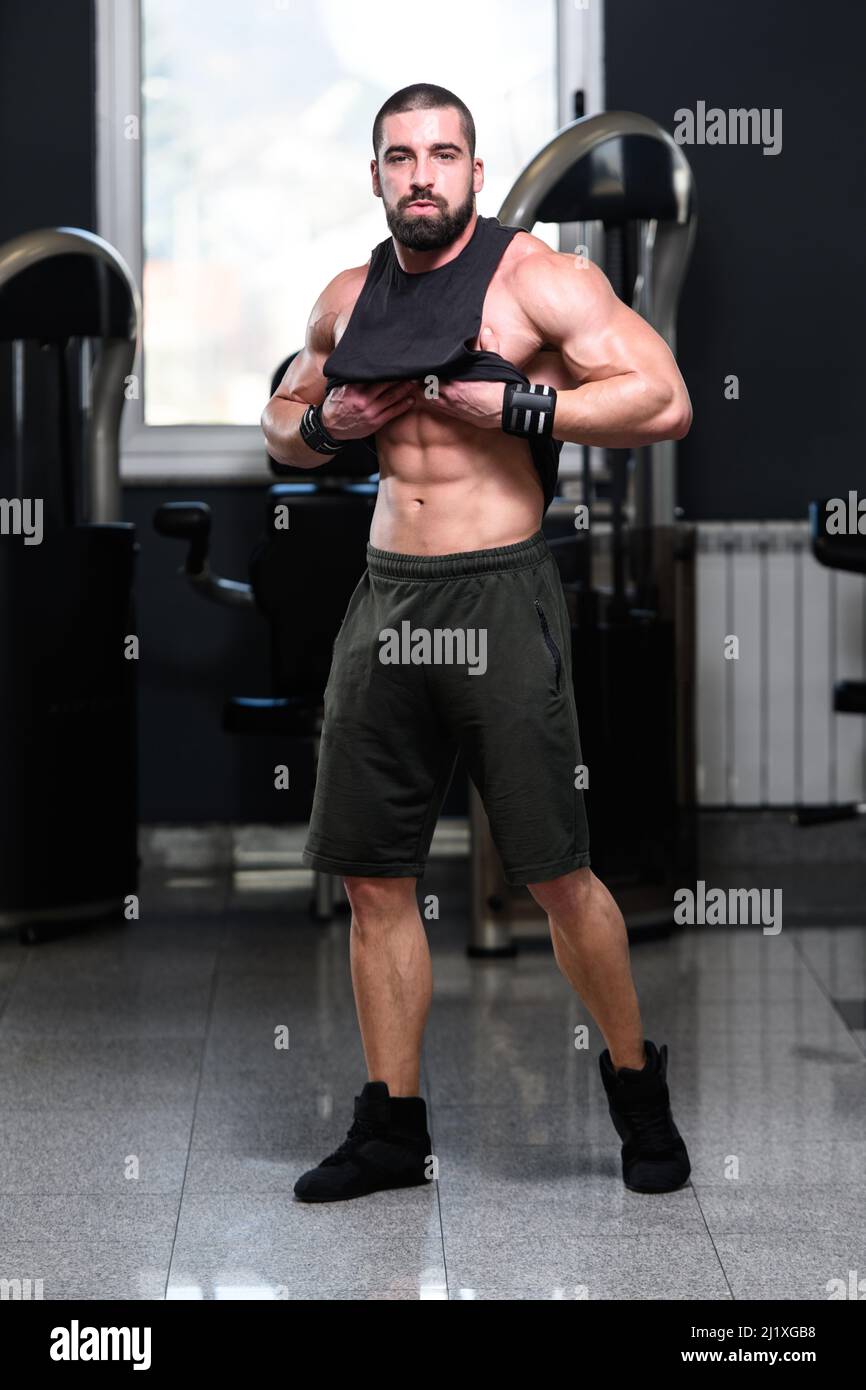 Young Man Standing Strong In The Gym And Flexing Muscles - Muscular ...