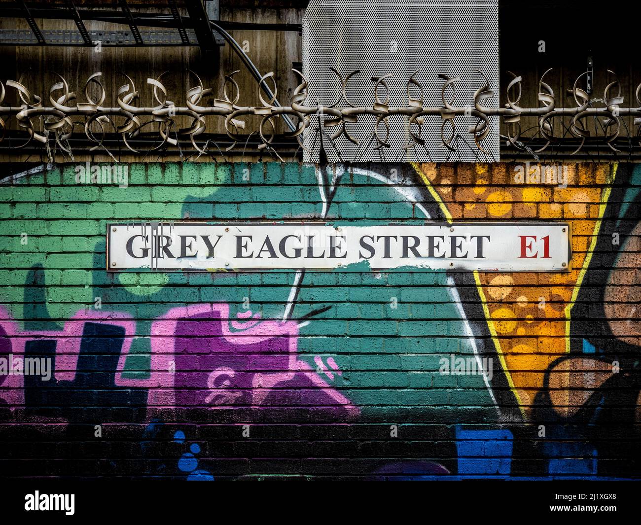 Road sign for Grey Eagle Street mounted on a wall with colourful ...