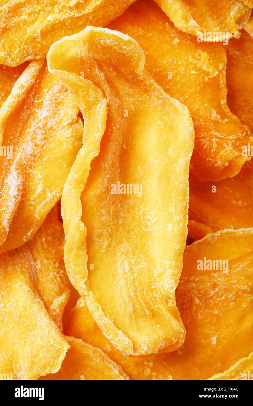 Pieces of sweet dried mango close-up as a background in full screen top ...