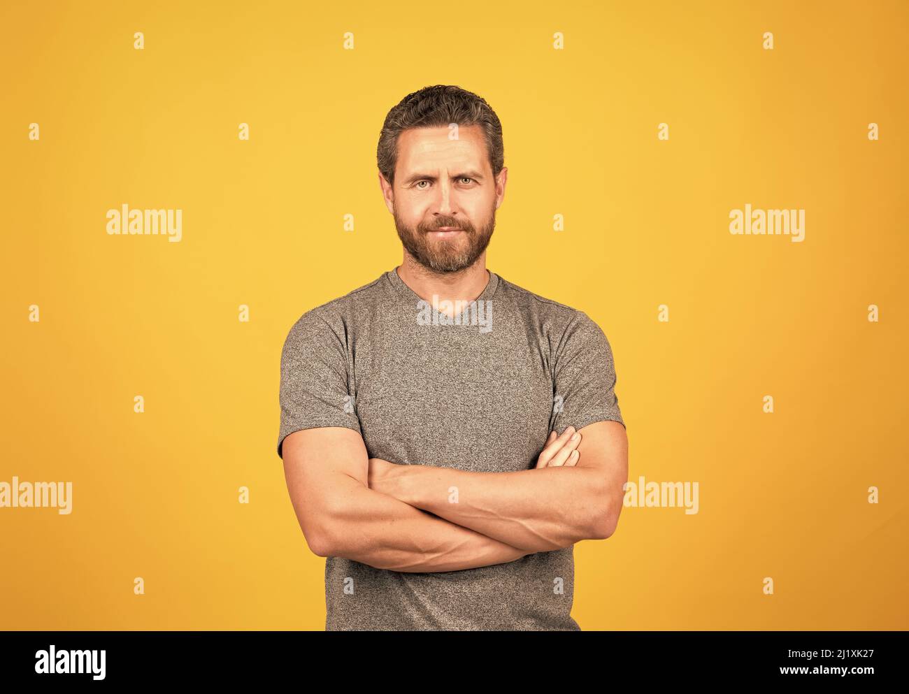 handsome mature muscular man with beard smiling on yellow background ...