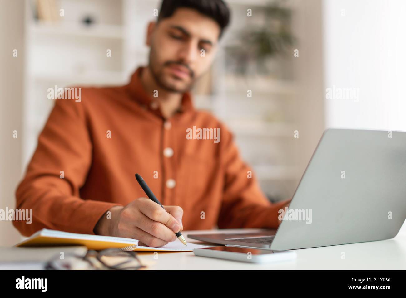 Portrait of focused Arab man using pc and writing Stock Photo - Alamy