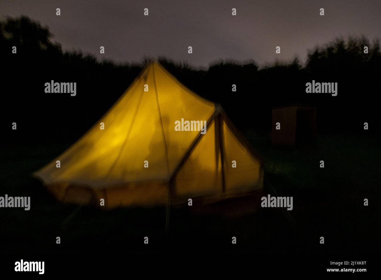 Night time view of a tent glowing from the inside on a glamping ...