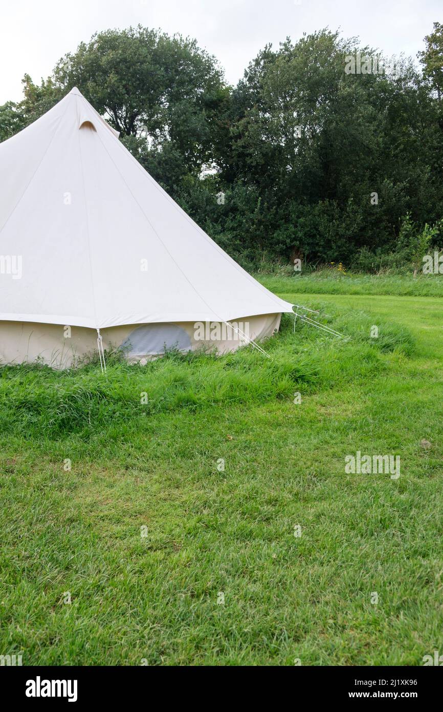 An old style canvas bell tent at a camp site in a lush green field set ...