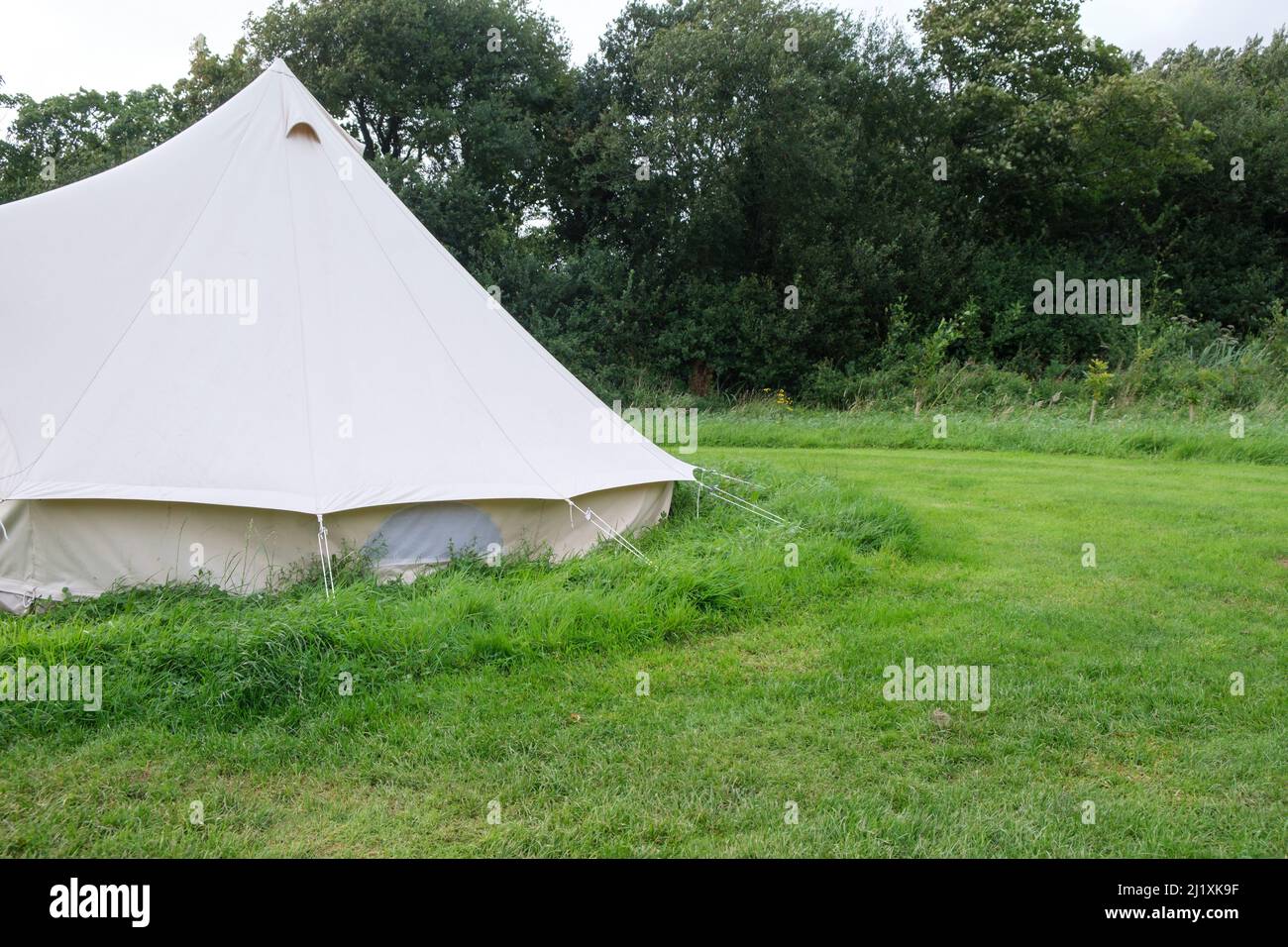 An old style canvas bell tent at a camp site in a lush green field set ...